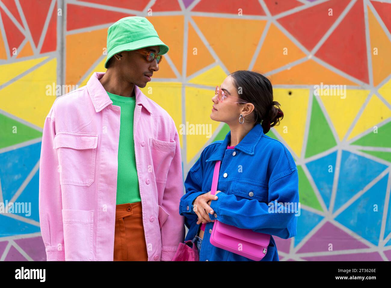 Multiracial couple talking in front of colorful wall Stock Photo - Alamy