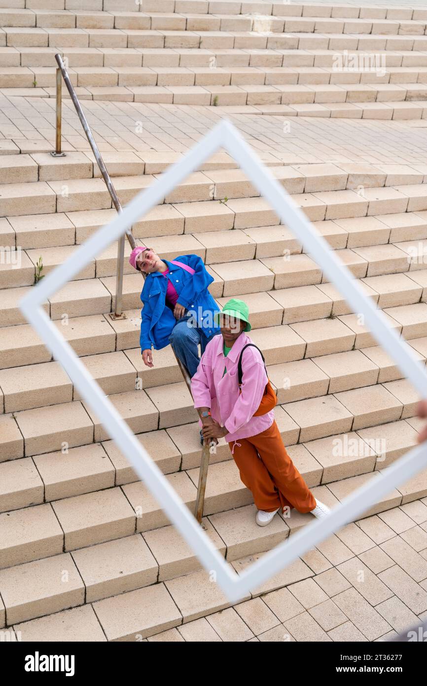 Cropped hand holding picture frame with couple standing on staircase ...