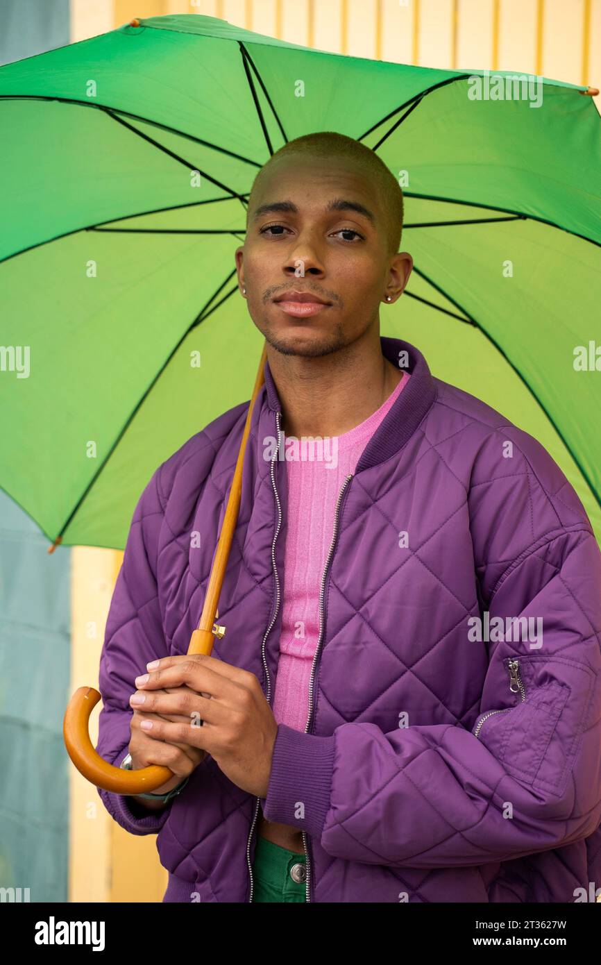 Non-binary person holding green umbrella Stock Photo - Alamy