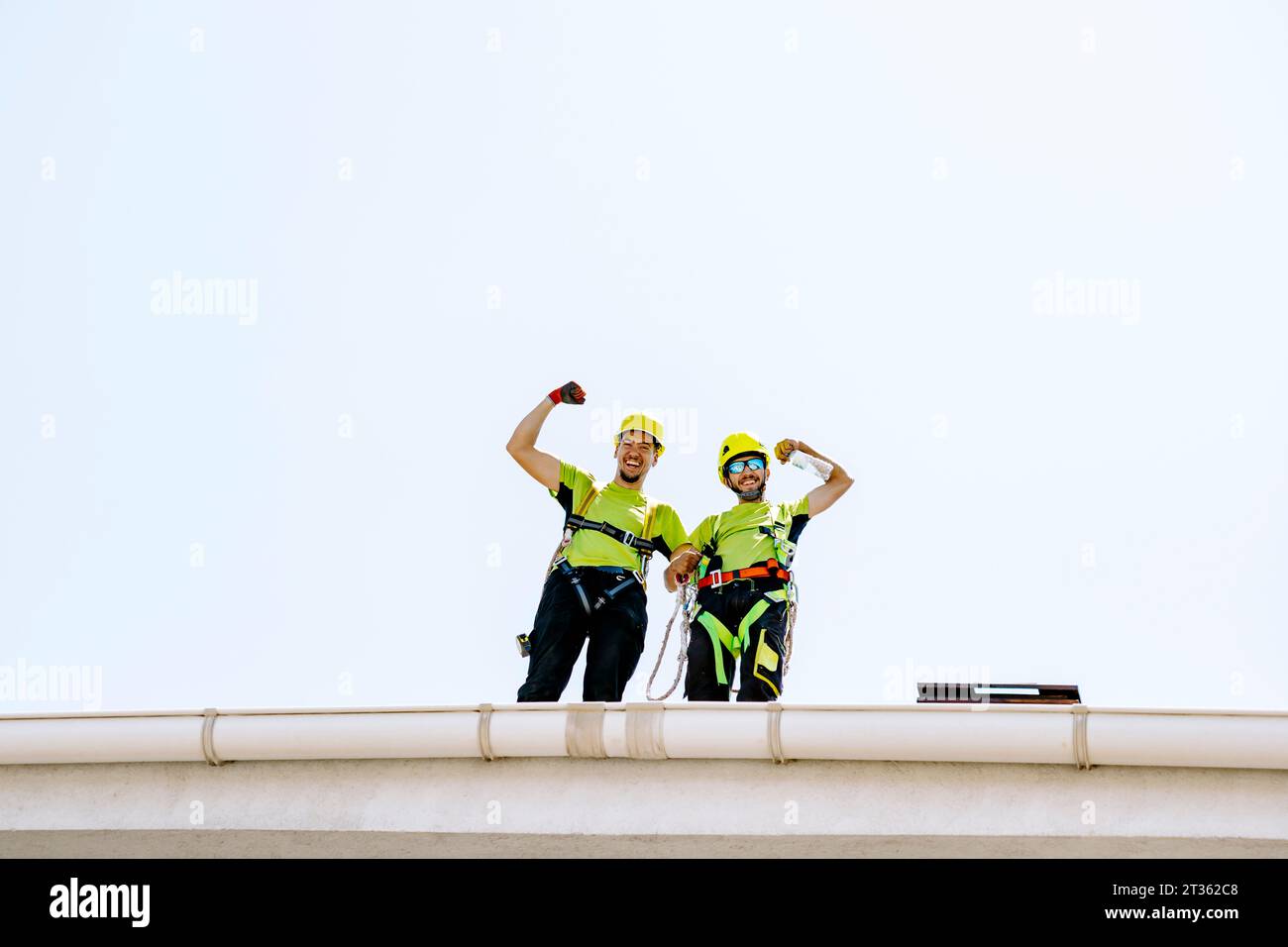 Happy engineers flexing muscles under sky Stock Photo - Alamy