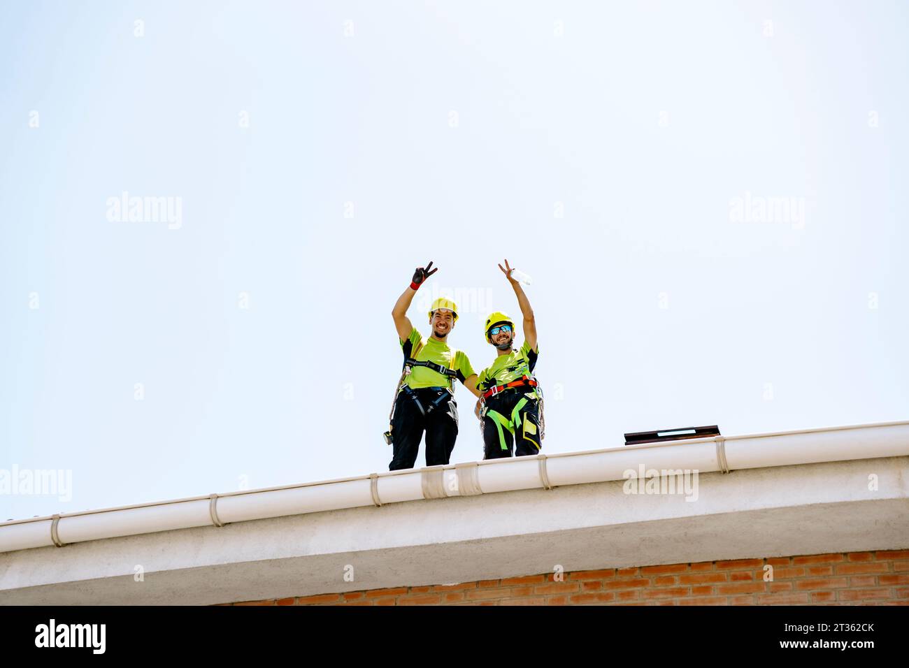 Happy engineers showing victory sign gesture under sky Stock Photo - Alamy