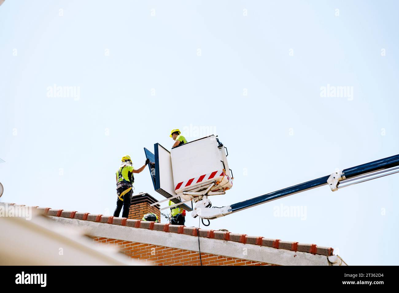 Engineers with colleague holding solar panel on hydraulic platform ...