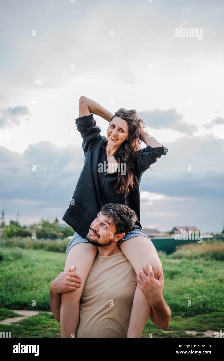 Smiling man carrying woman on shoulders in the countryside Stock Photo ...