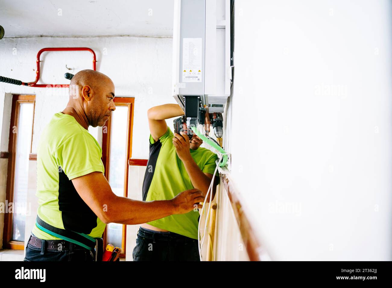 Engineer with colleague using drill machine Stock Photo - Alamy