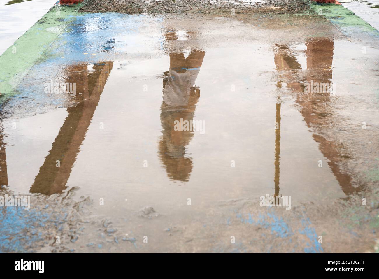 Reflection of an unidentified person in the puddle of water on the ...