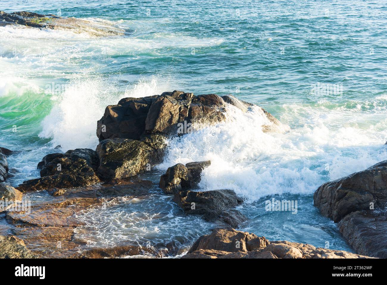Sea waves lapping gently on the dark rocks of the beach. Preserved and ...