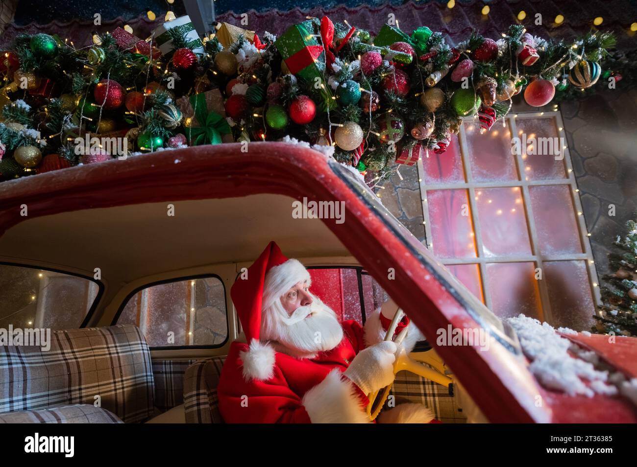 Portrait of santa claus driving a car loaded with a Christmas tree and ...