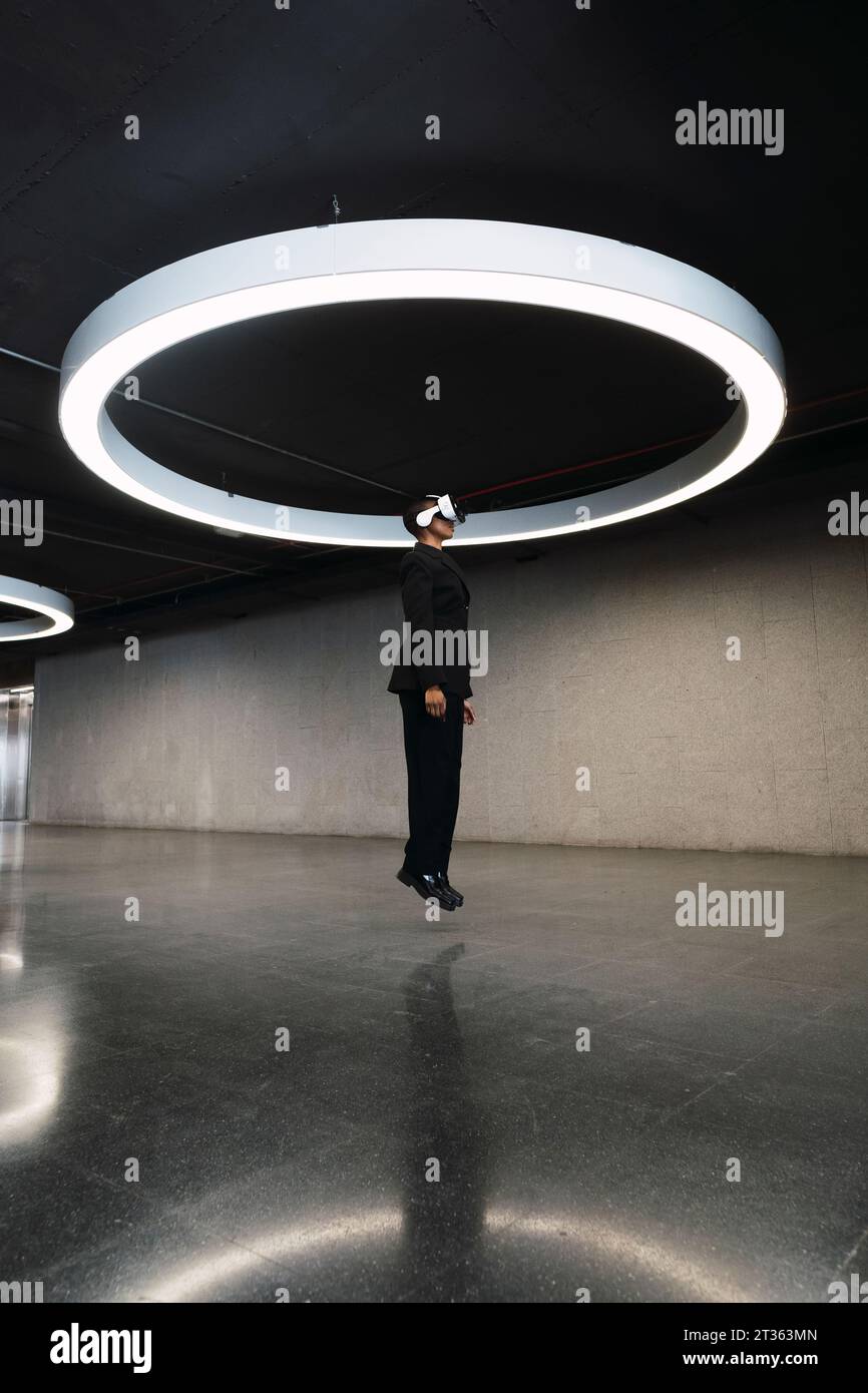 Young woman using VR glasses and jumping in parking garage Stock Photo ...