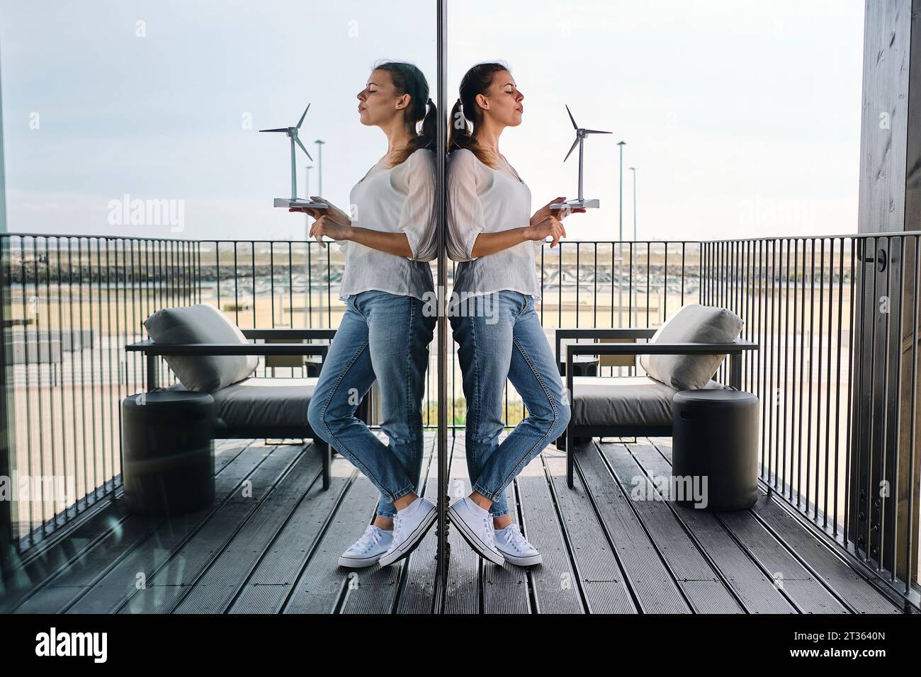 Portrait of pretty blonde leaning on glass wall with model of wind ...