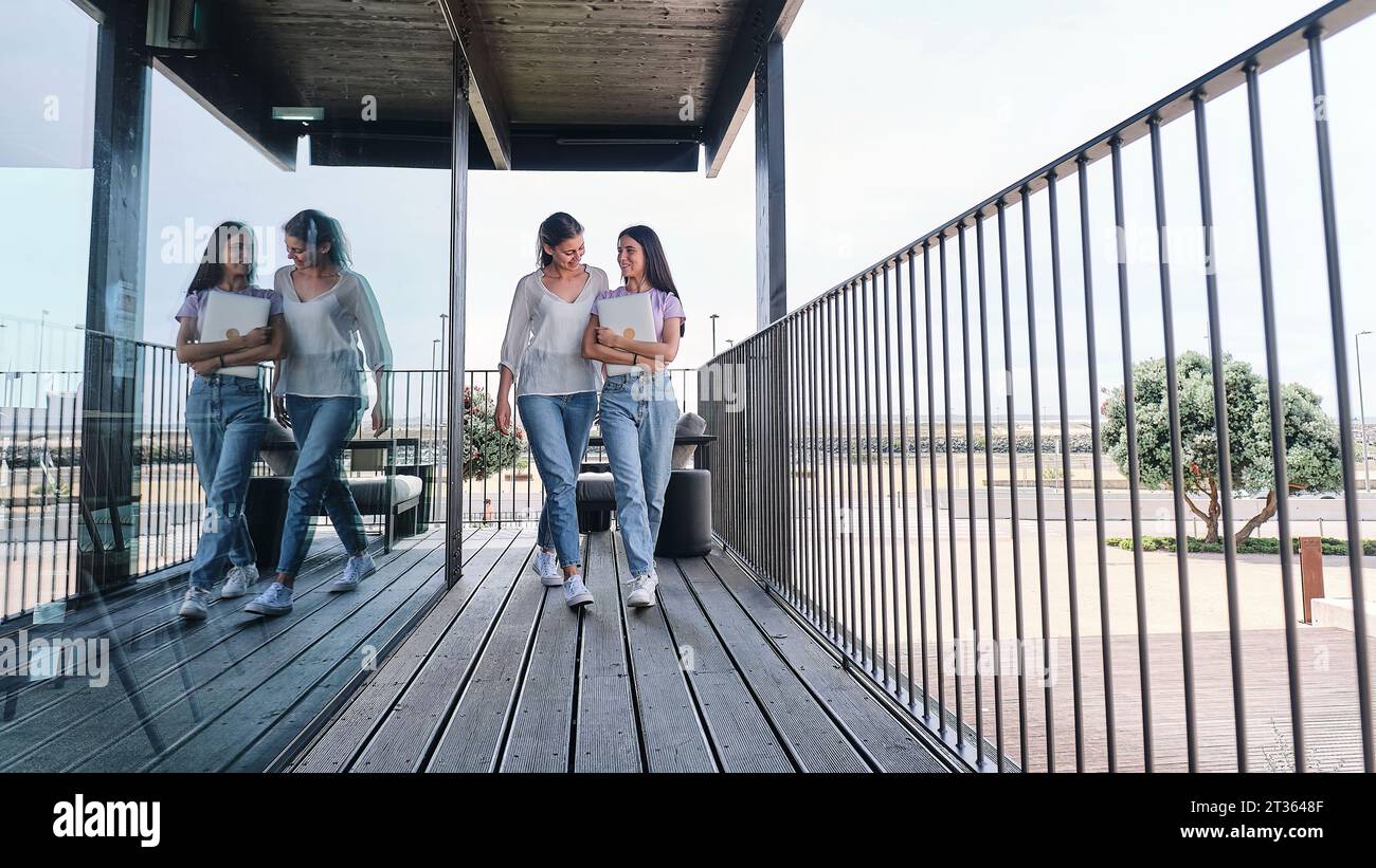 Two young women walking side by side on balcony Stock Photo - Alamy