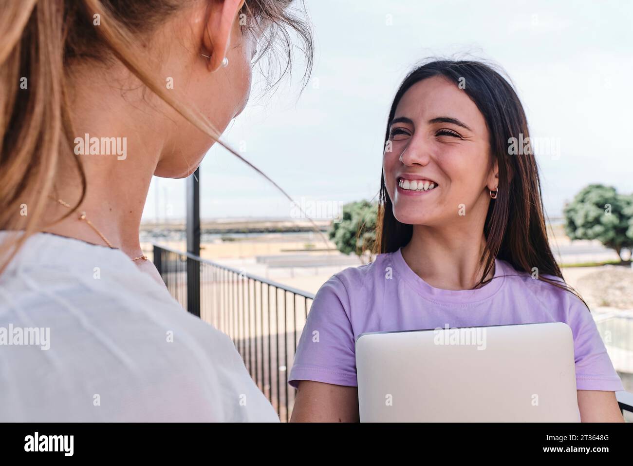 Two young women talking on balcony Stock Photo - Alamy
