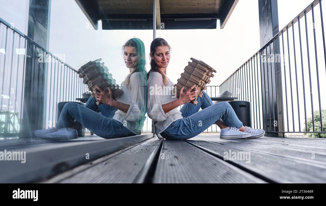 Portrait of pretty blonde woman sitting on balcony with cardboard box ...