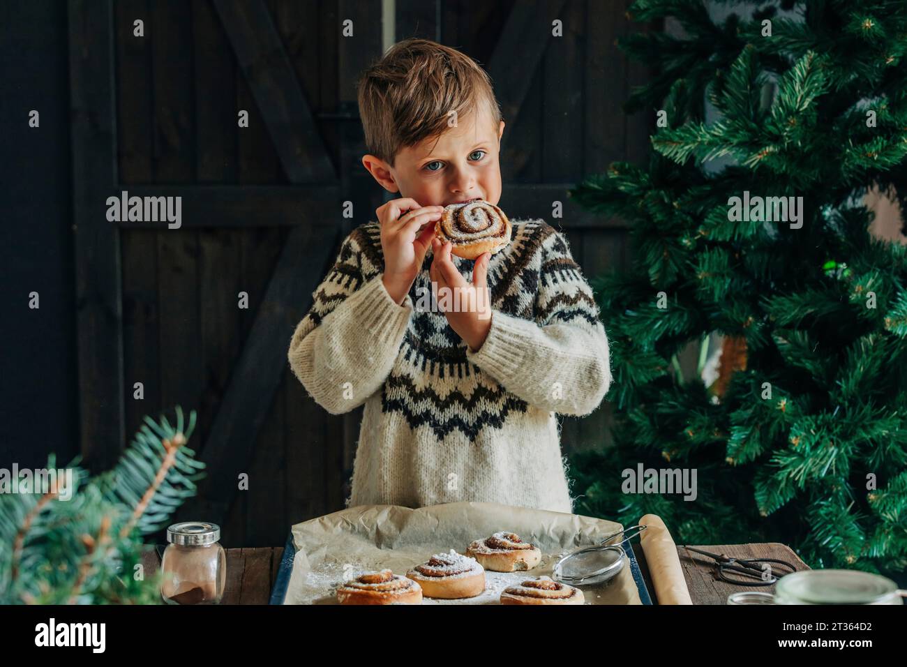 Boy eating cinnamon bun at table Stock Photo - Alamy