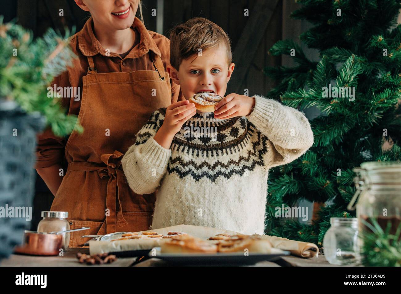 Son eating cinnamon bun at table Stock Photo - Alamy