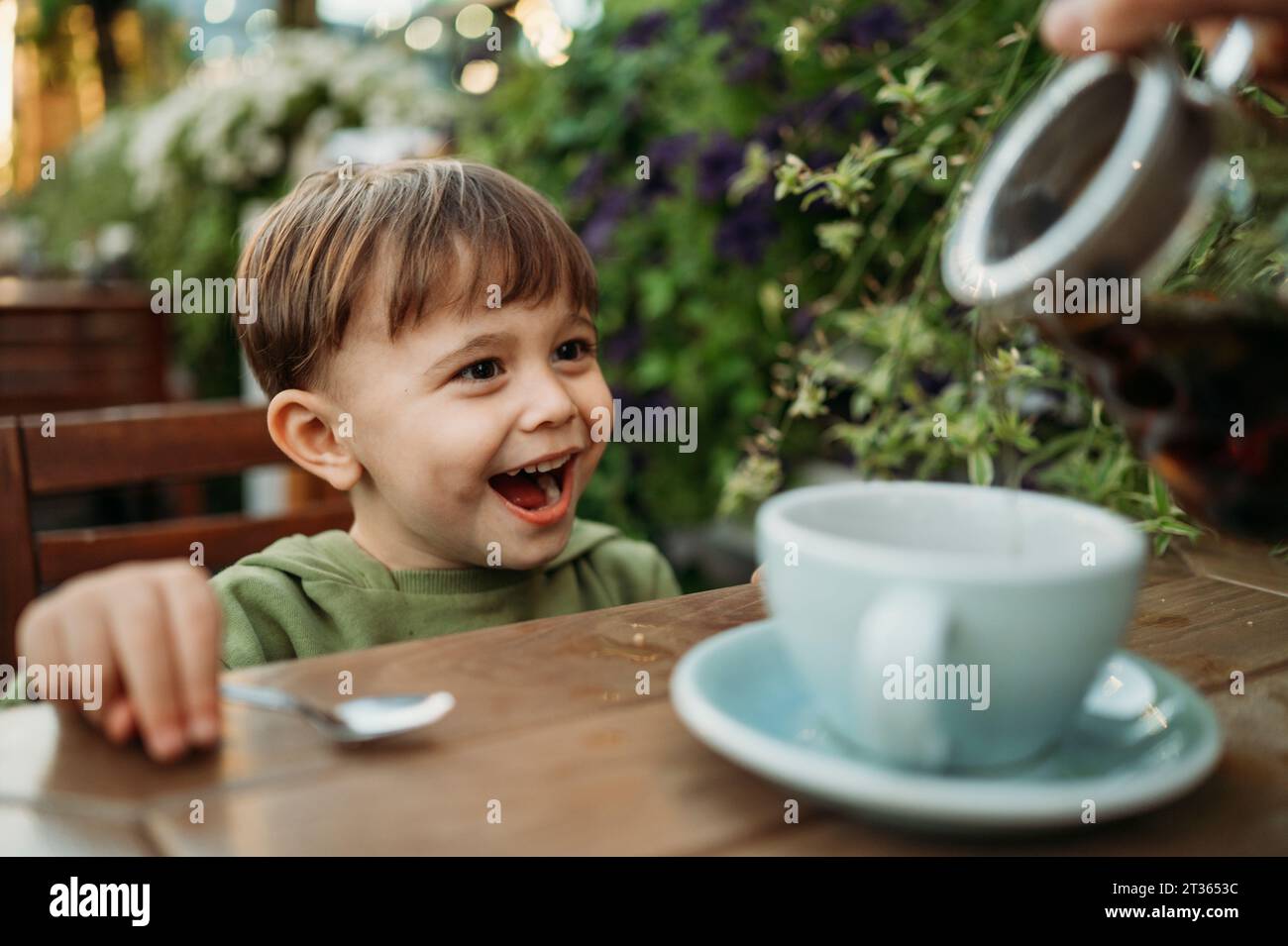 Happy boy with mother pouring tea in cup Stock Photo - Alamy