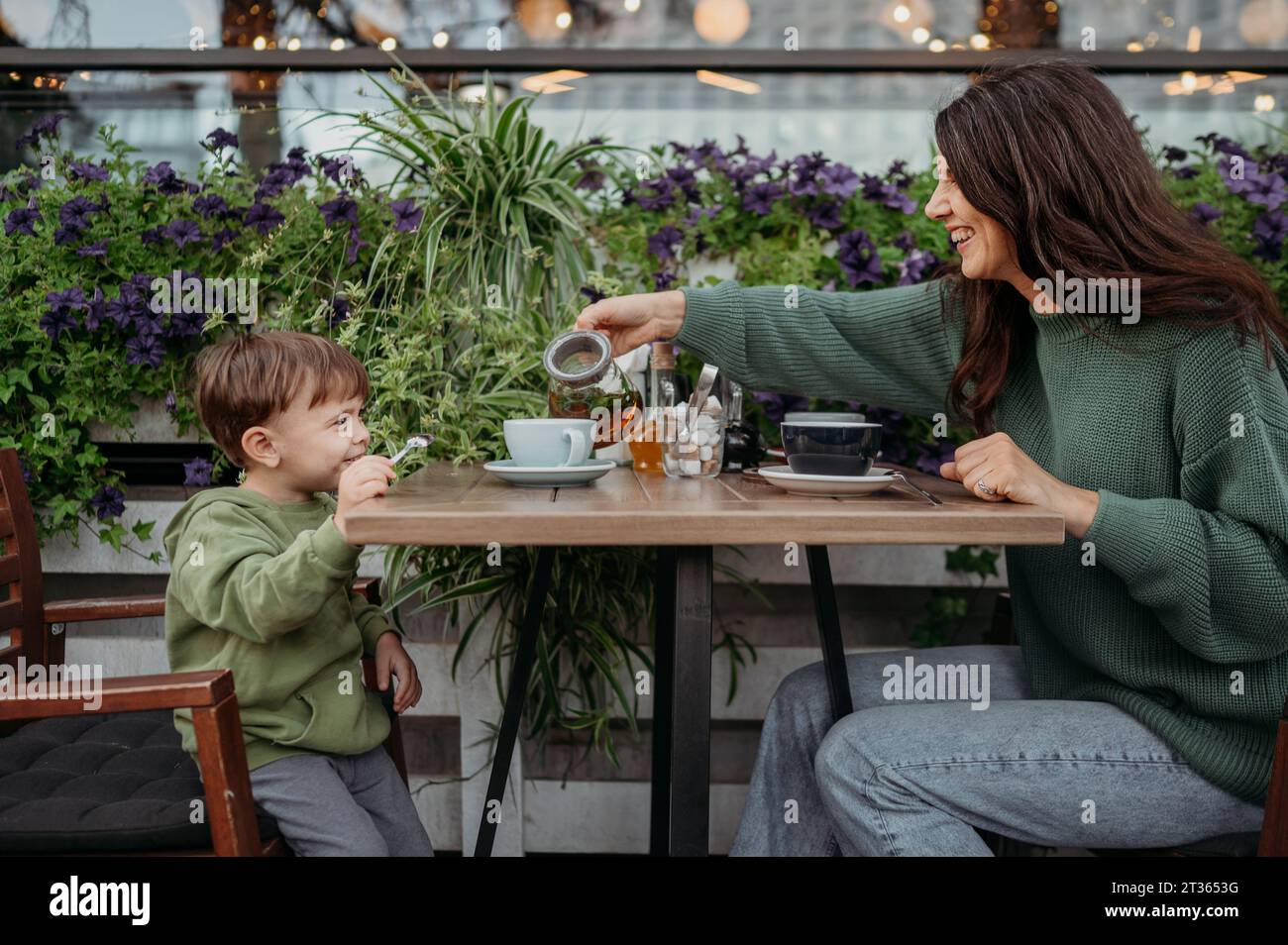 Happy boy with mother serving tea in cup at cafe Stock Photo - Alamy