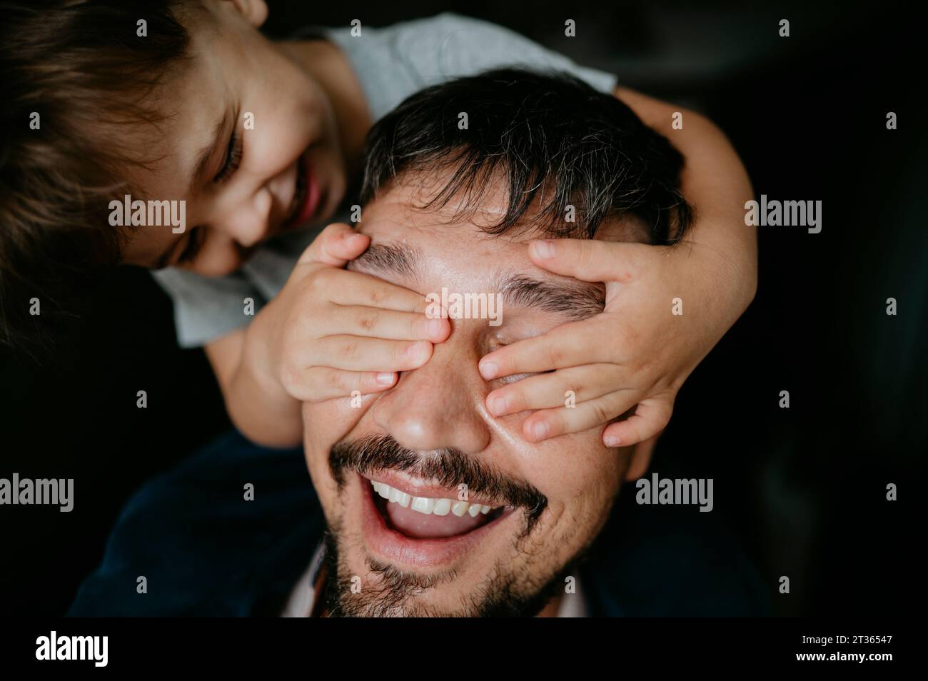 Smiling son covering father's eyes Stock Photo - Alamy