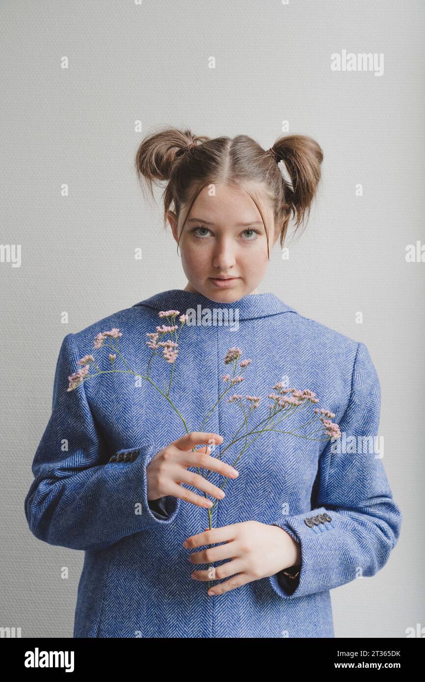 Teenage girl wearing blue blazer backwards and holding flowers in front ...