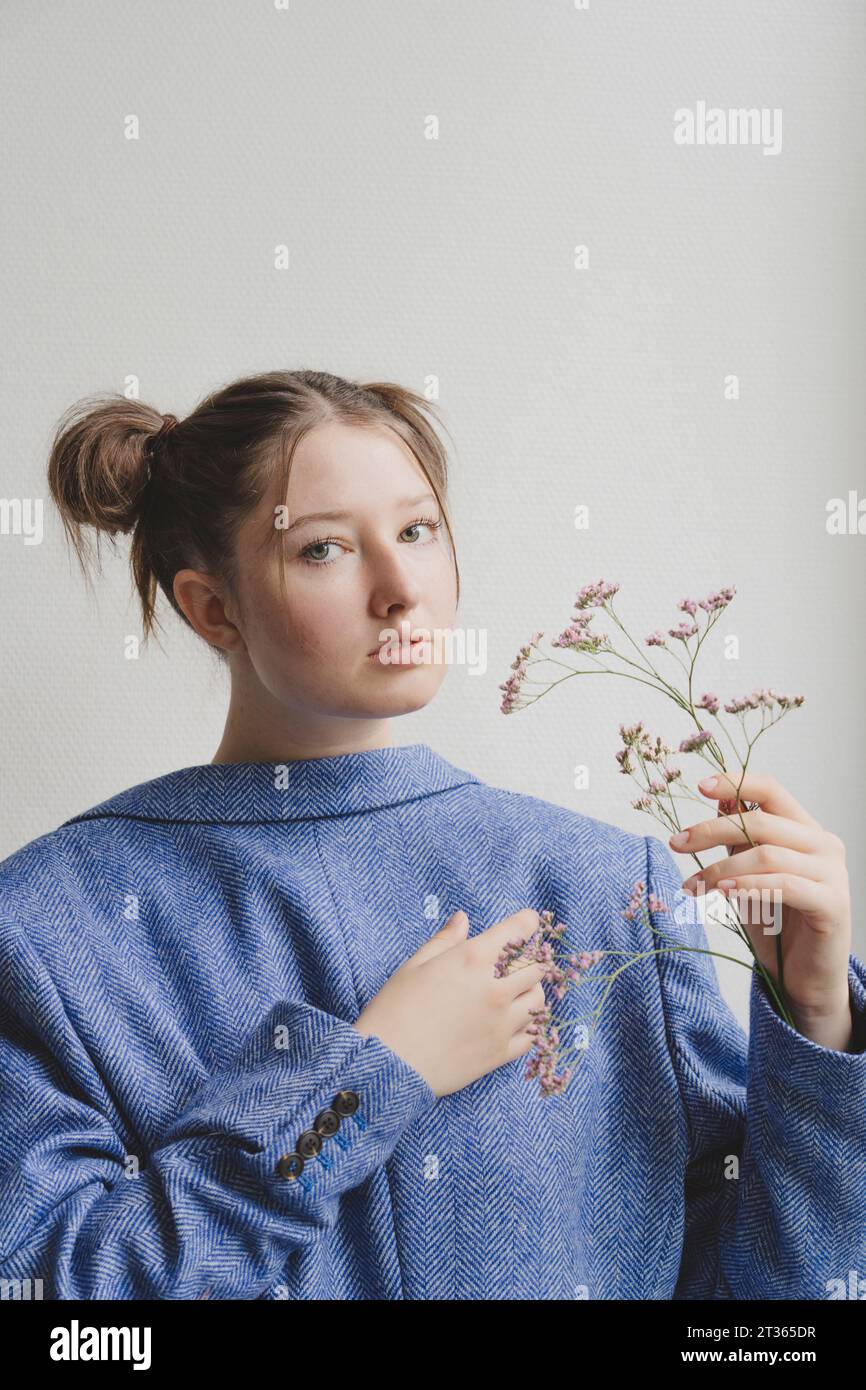 Teenage girl wearing blue blazer backwards with flowers in front of ...