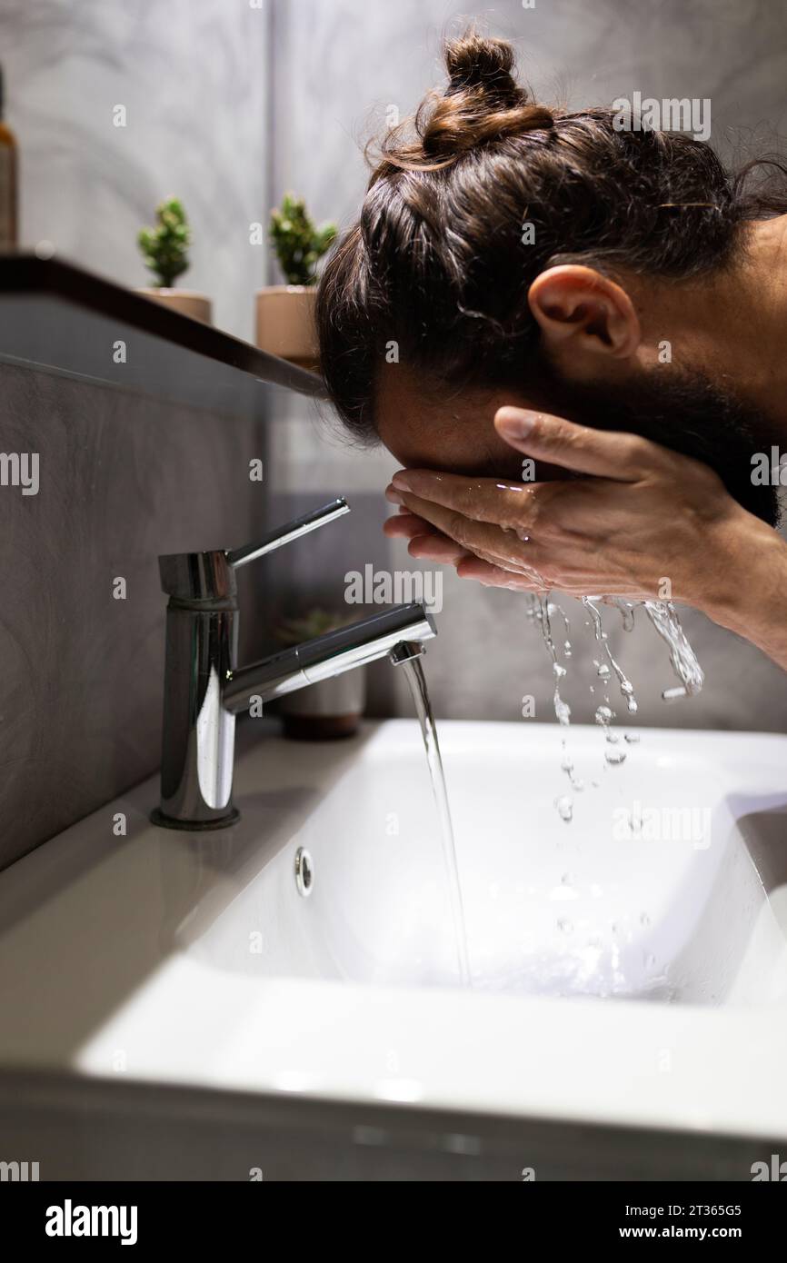 Man washing face in bathroom sink Stock Photo - Alamy