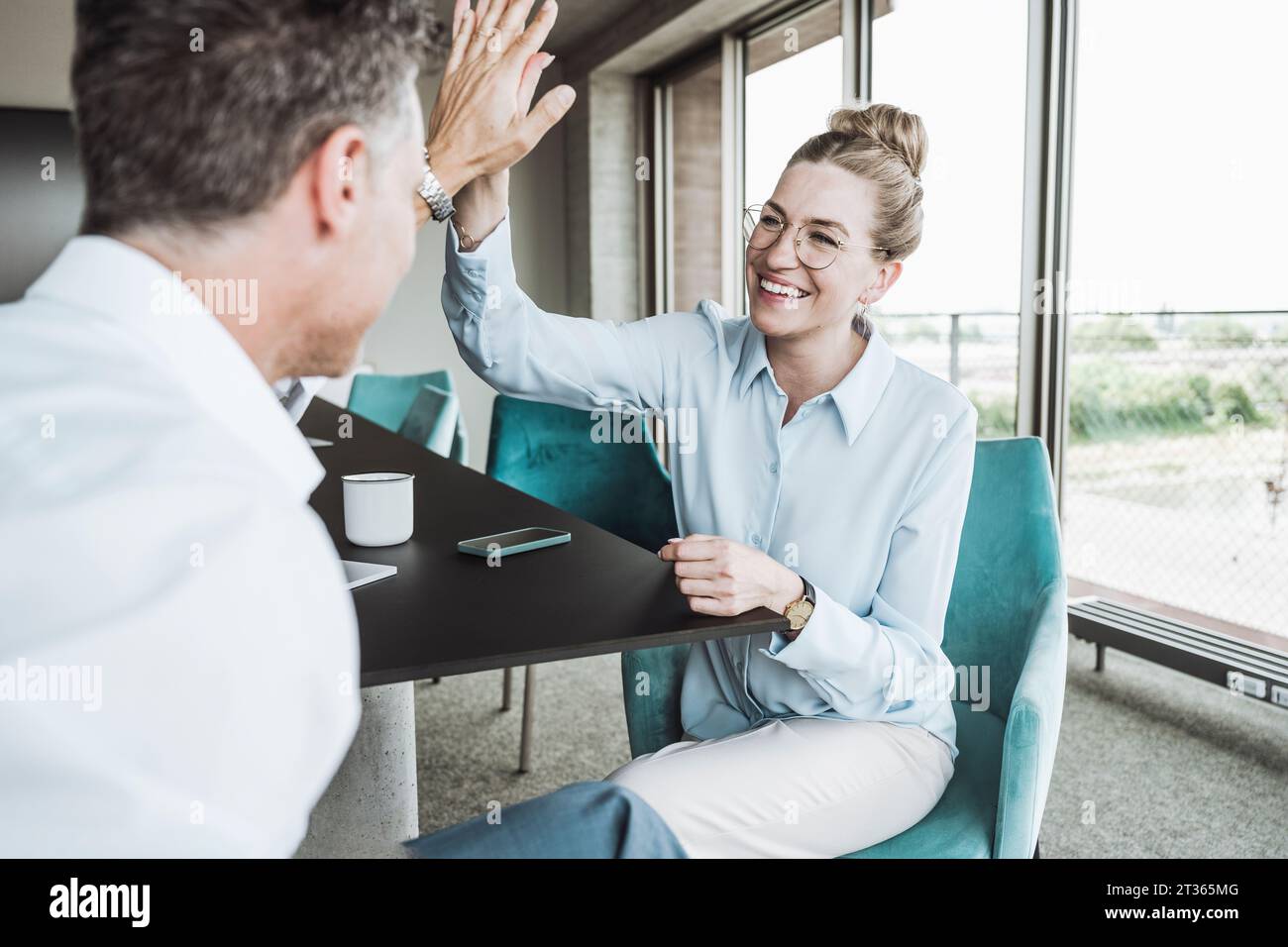 Happy businesswoman giving high-five to colleague in office Stock Photo ...