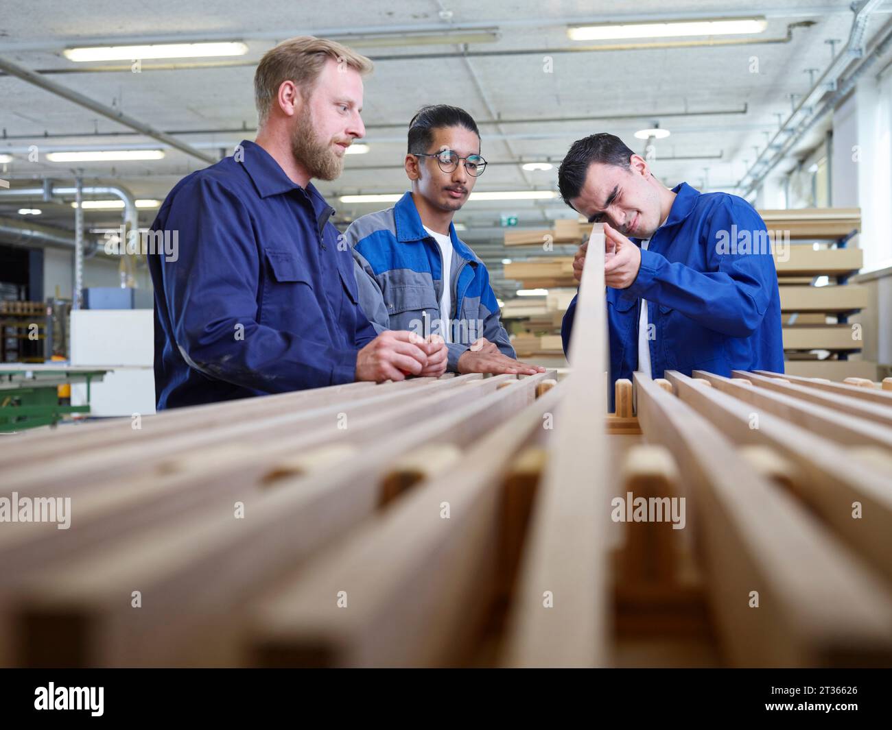 Trainee checking quality of wooden plank in factory Stock Photo - Alamy
