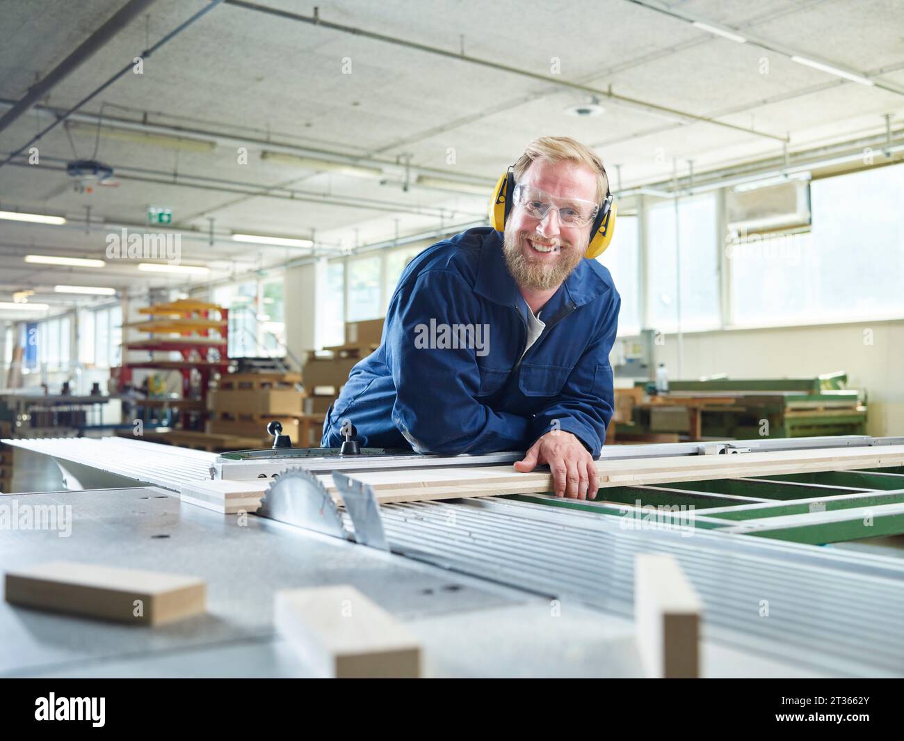 Smiling carpenter wearing protective workwear in factory Stock Photo ...