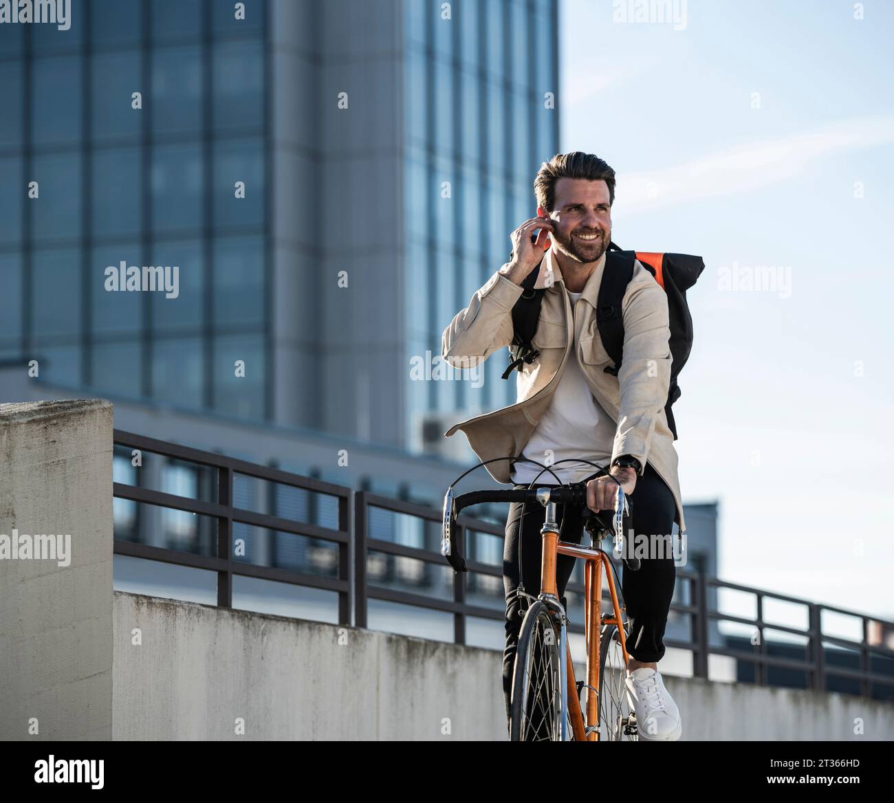 Man riding bicycle in front of building Stock Photo - Alamy