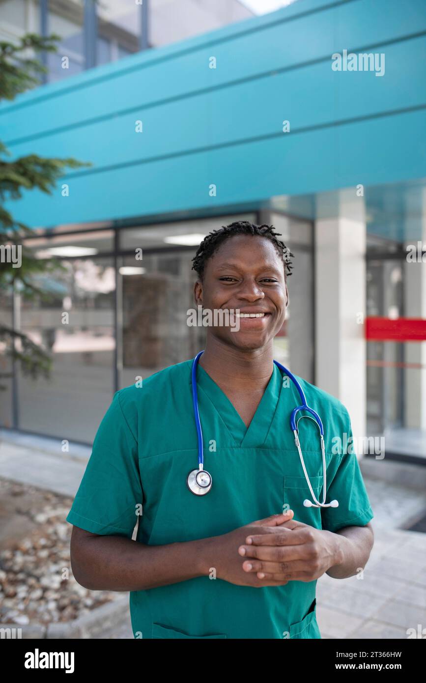 Smiling young doctor standing in front of hospital Stock Photo - Alamy