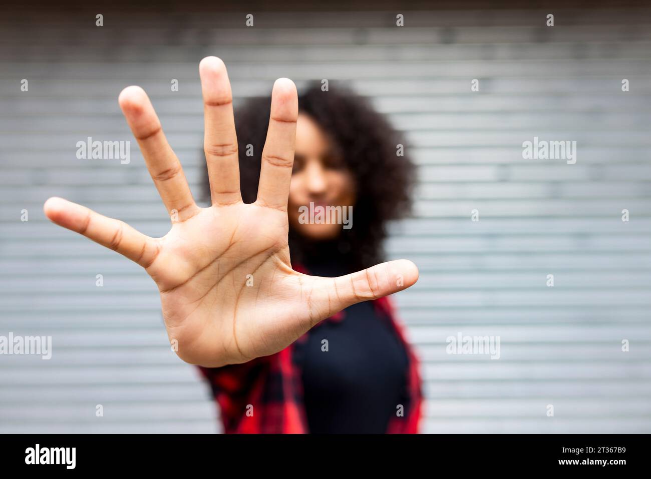 Woman showing stop sign gesture in front of shutter Stock Photo - Alamy
