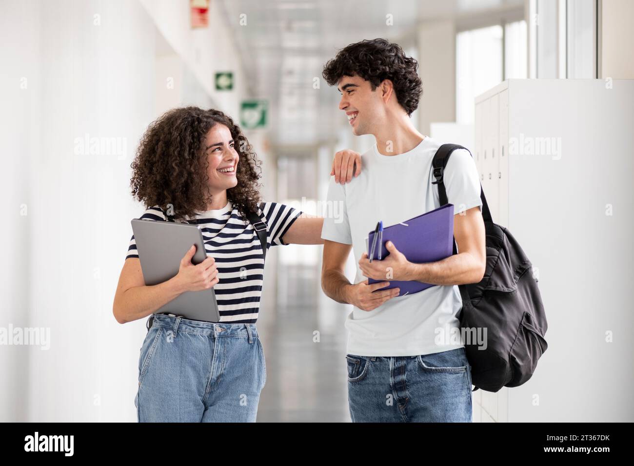 Smiling students talking in corridor Stock Photo - Alamy