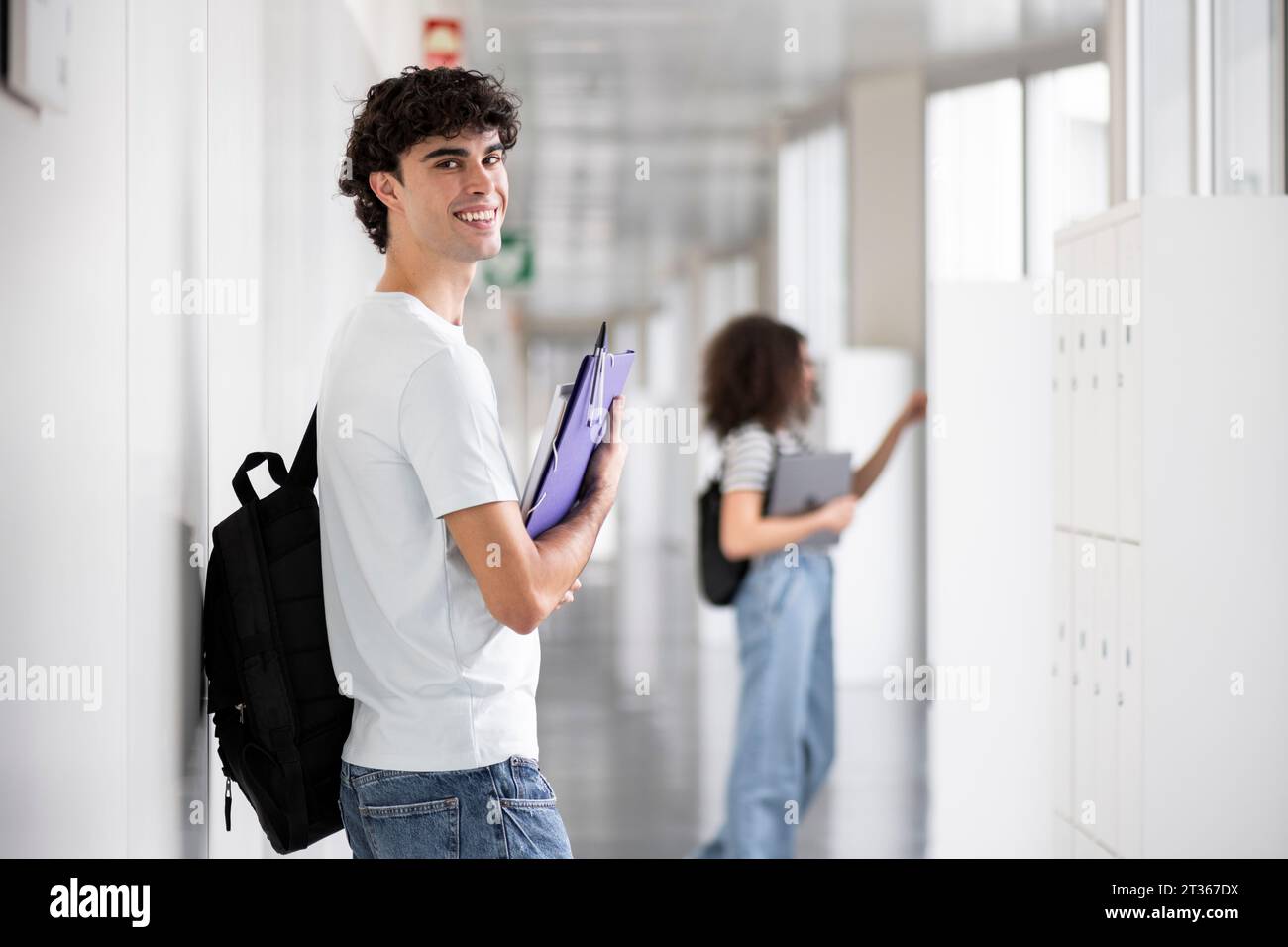 Happy student holding file folder in corridor Stock Photo - Alamy