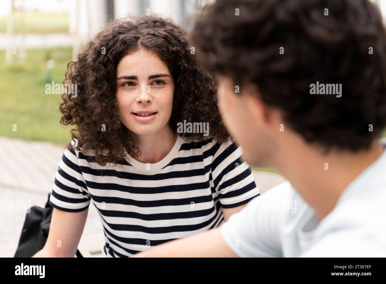 Smiling student talking with friend in campus Stock Photo - Alamy