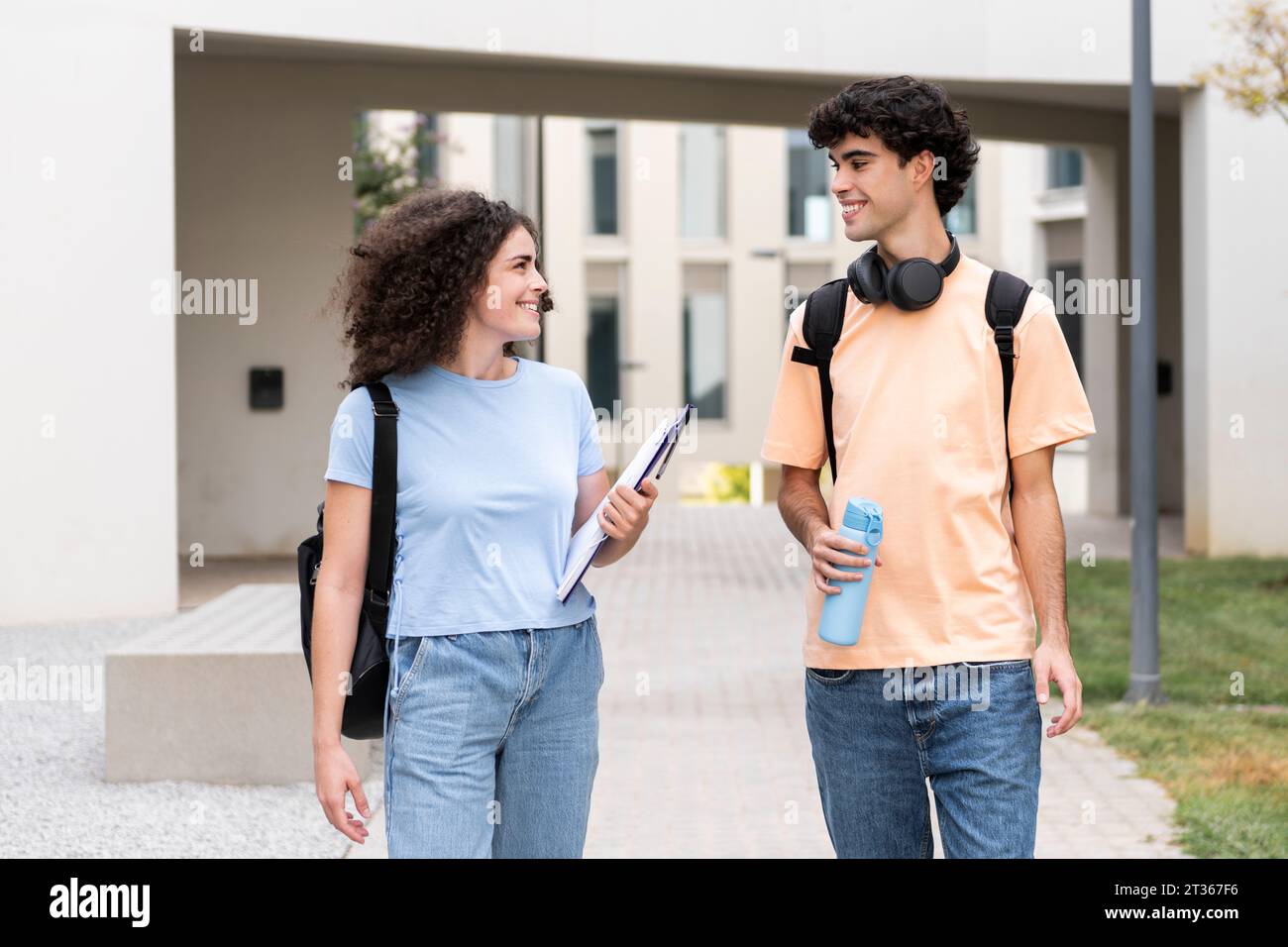 Smiling students standing in front of building at campus Stock Photo ...