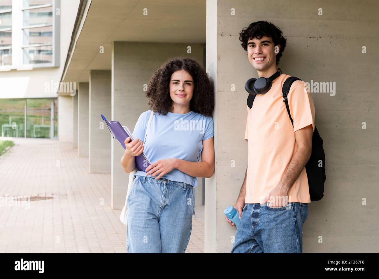Smiling students leaning on wall in campus Stock Photo - Alamy