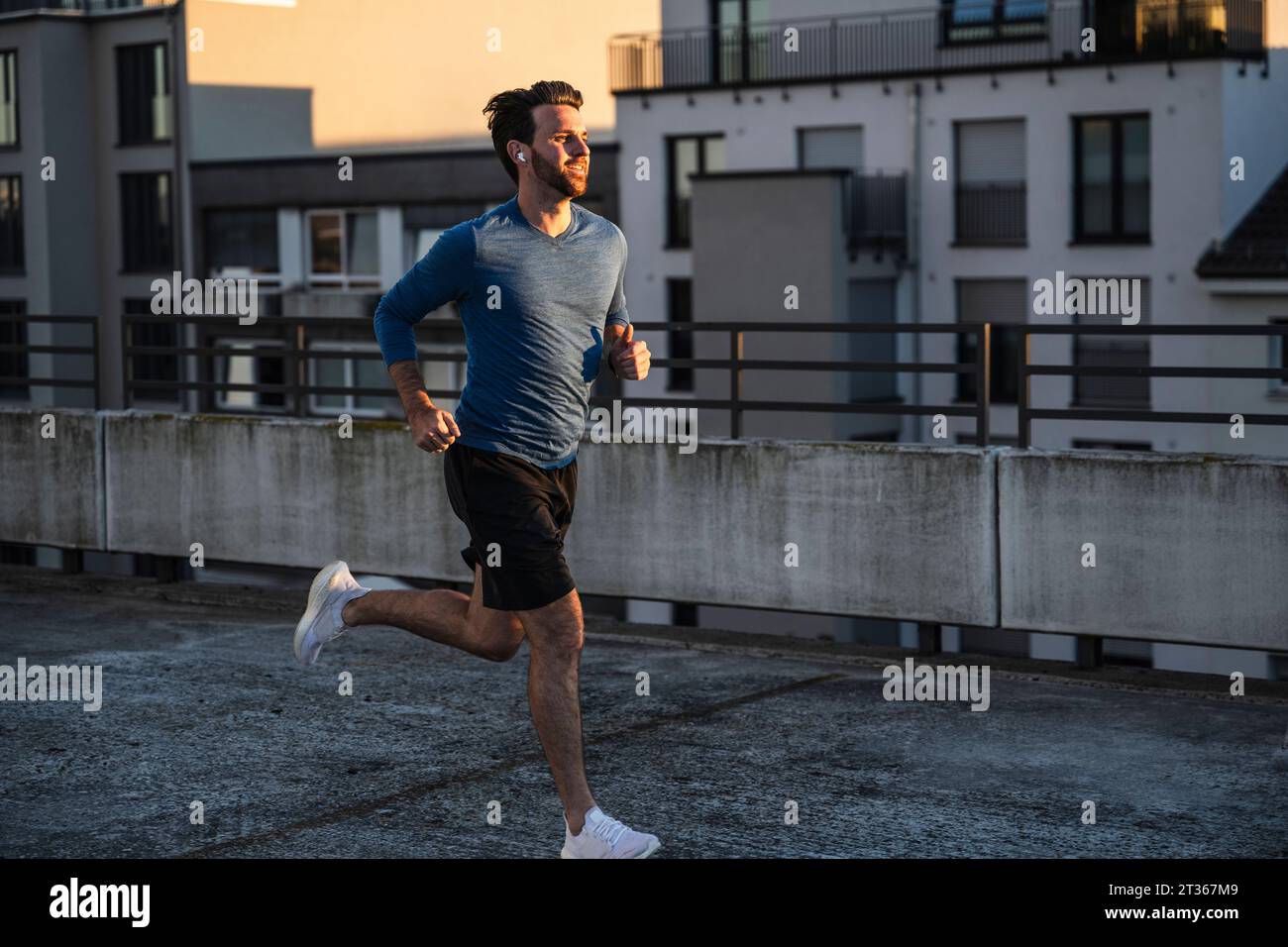 Active man running near railing on terrace at sunset Stock Photo - Alamy
