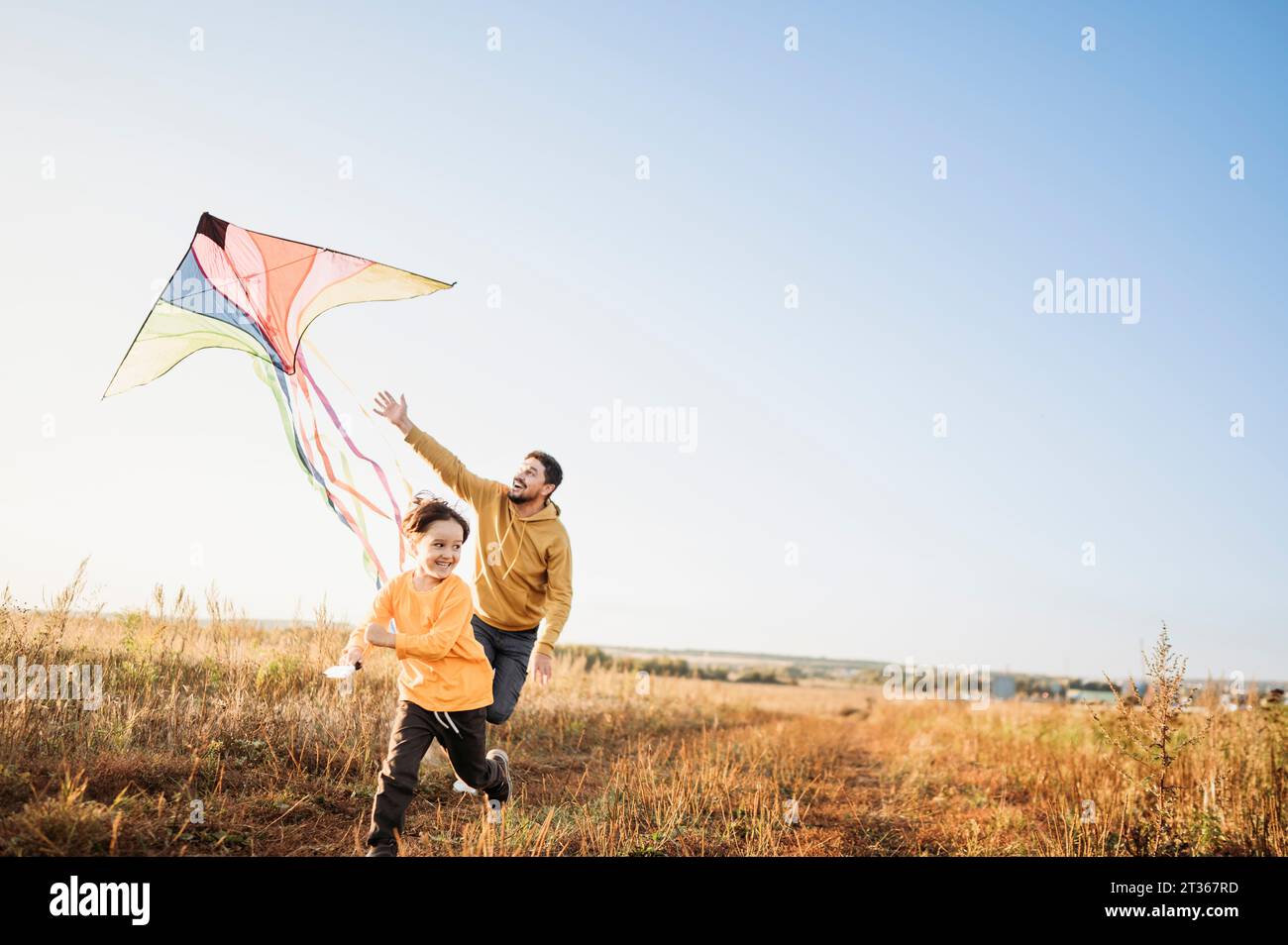 Happy father and son flying kite in field Stock Photo - Alamy
