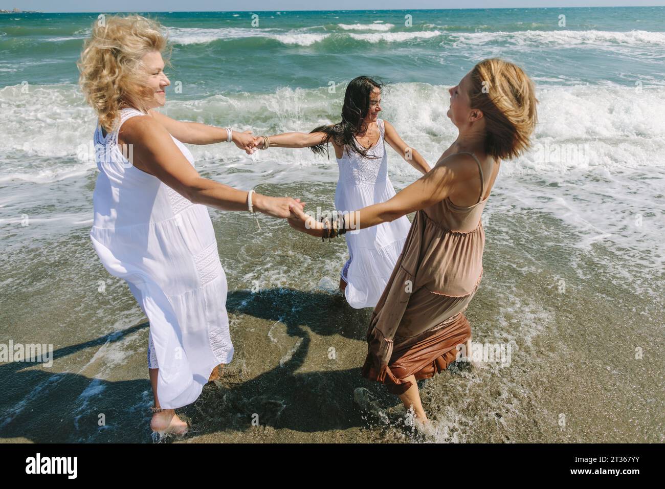 Carefree friends playing ring around the rosy near sea at beach Stock ...