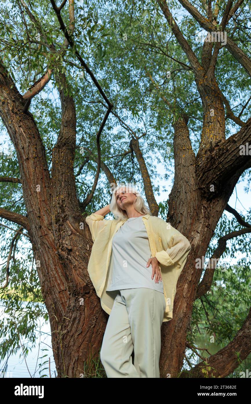 Mature woman leaning tree hi-res stock photography and images - Alamy