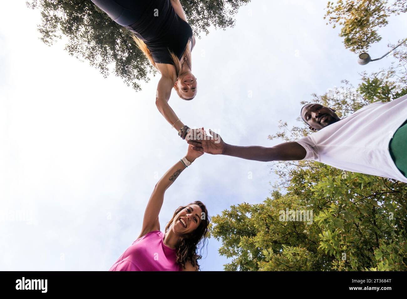 Smiling multiracial friends stacking hands under sky Stock Photo - Alamy