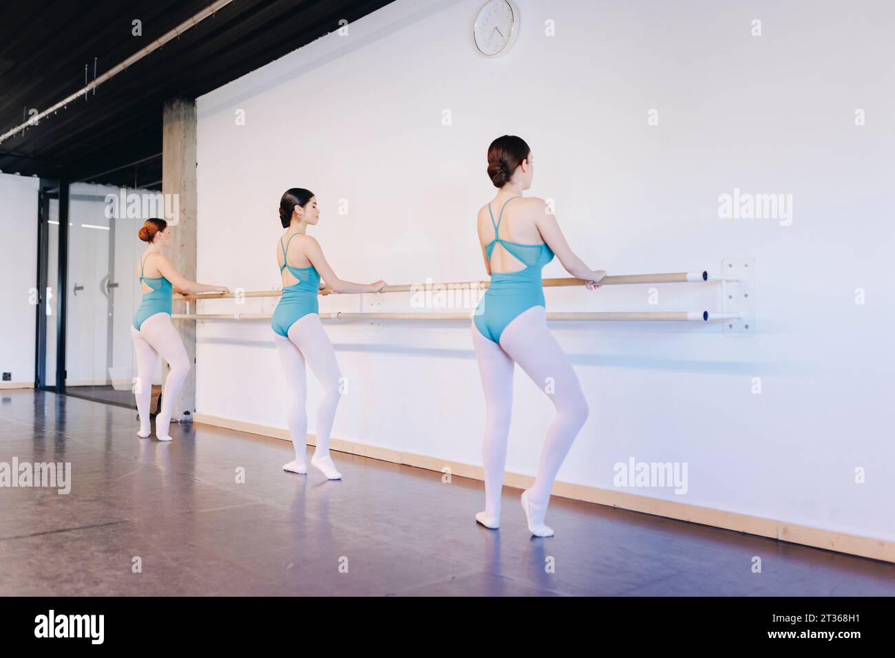 Ballet dancers stretching by railing near wall in dance school Stock ...