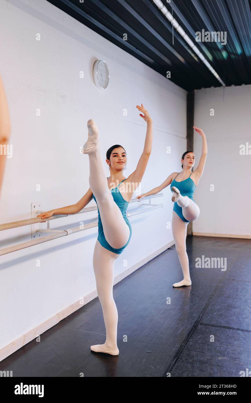 Dancers practicing ballet standing on one leg in dance school Stock ...