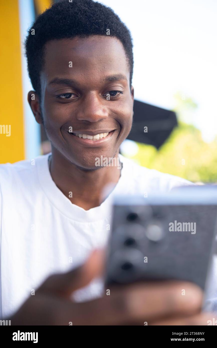 Smiling young man using phone by computer in the office Stock Photo - Alamy