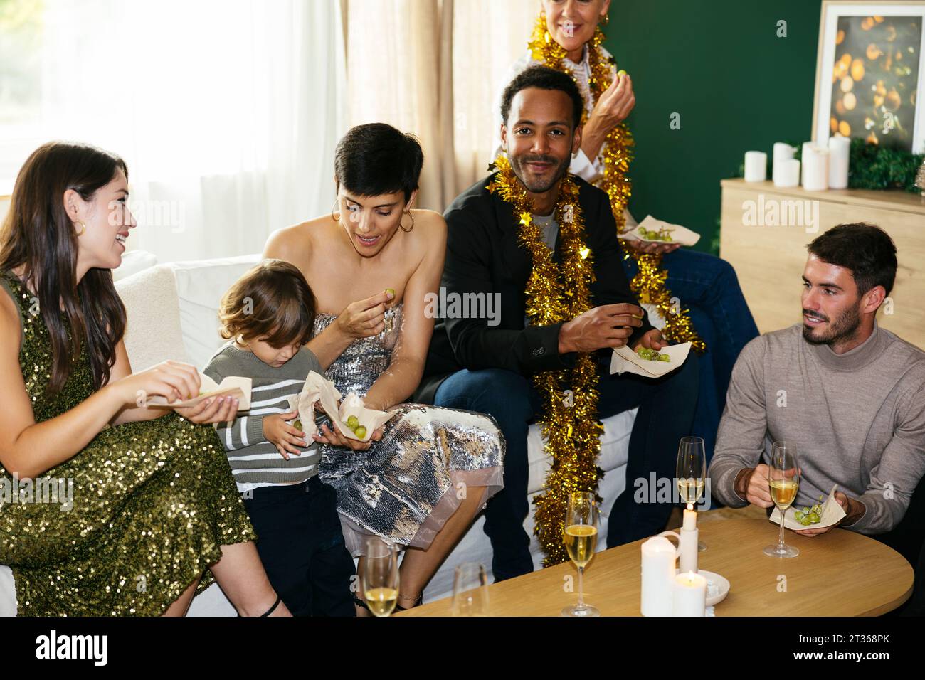 Multi-generation family having food at new year party in living room at ...