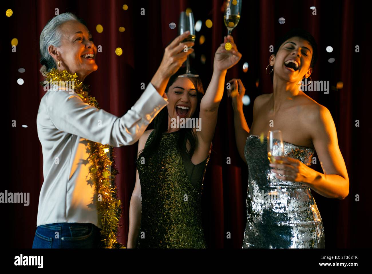 Cheerful women with drinking glasses dancing at new year Stock Photo ...