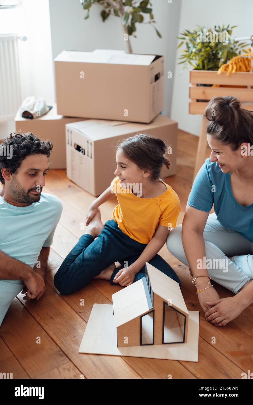 Girl sitting with parents and model house on floor Stock Photo - Alamy