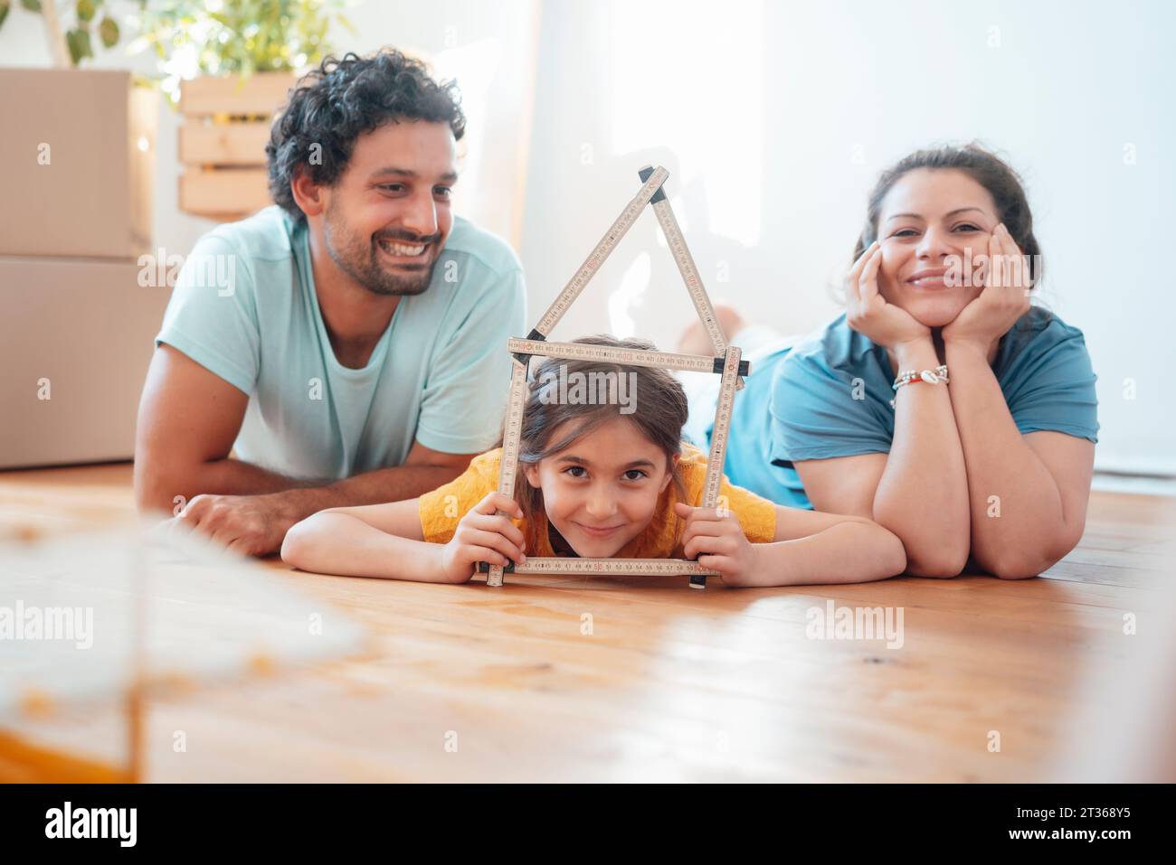 Happy parents with daughter holding model house on floor Stock Photo ...