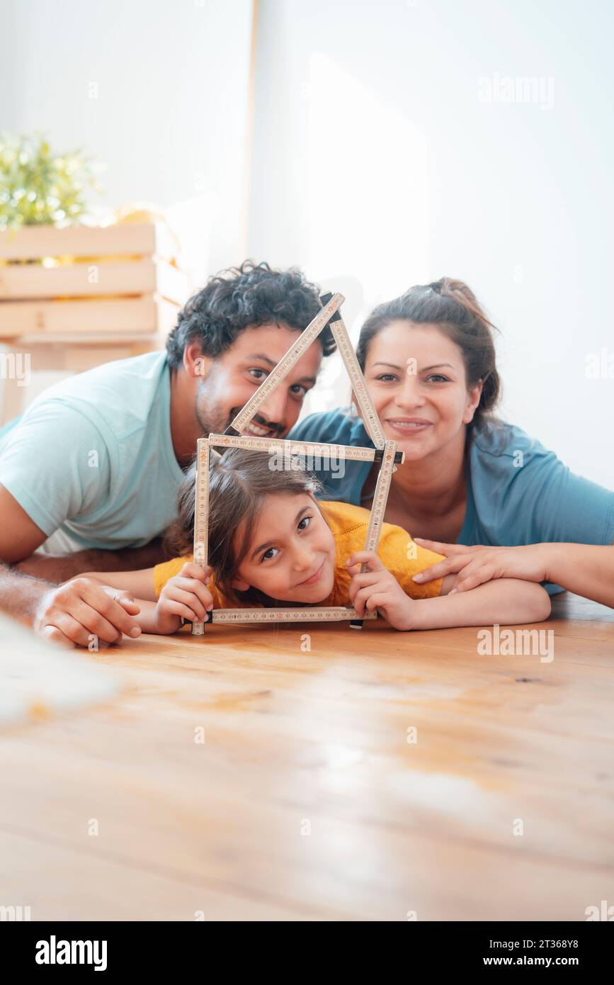 Smiling parents with daughter holding model house on floor Stock Photo ...
