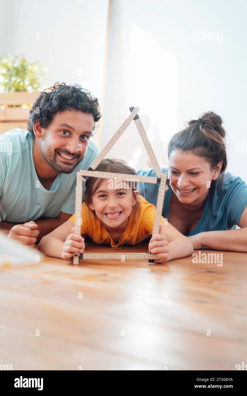 Happy parents with daughter holding model house on floor at home Stock ...