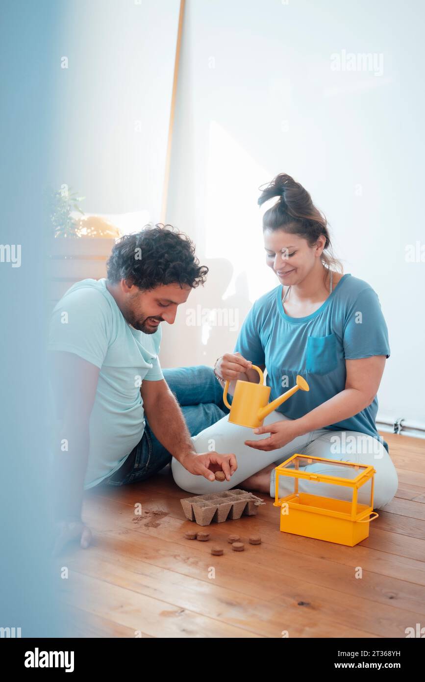 Happy man and woman planting seeds in seedling tray at home Stock Photo ...